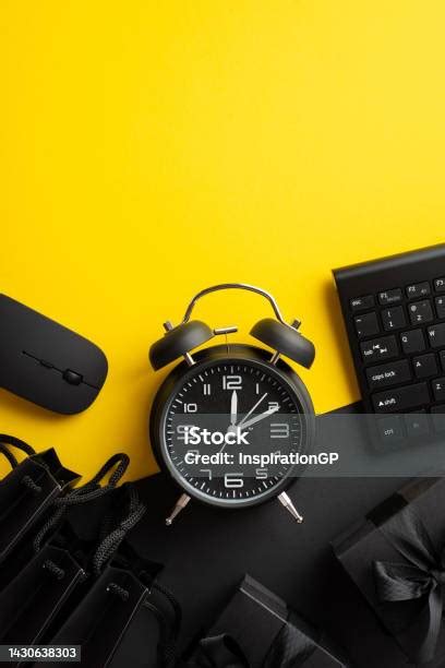 블랙 프라이데이 판매 개념 상단보기 수직 사진 알람 시계 키보드 컴퓨터 마우스 검은 종이 봉지와 선물 상자 이중 색상 노란색과 검은 색 배경에 11월에 대한 스톡 사진 및