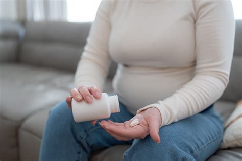 알아볼 수 없는 임산부 알약이 담긴 항아리를 들고 비타민을 복용하는 것 임신 중 질병을 치료하는 것 소파에 앉아 있는 것 닫기 가정 생활에 대한 스톡 사진 및 기타 이미지