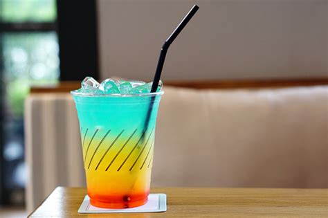 화려한 칵테일 또는 열 대 Mocktail레모네이드 에너지 음료의 플라스틱 유리 오렌지 주스와 수 박 시럽 나무 테이블에 배경