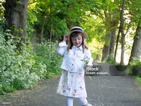 예쁜 어린 소녀가 꽃을 따고 있습니다 밀짚 모자를 쓴 햇볕이 잘 드는 아이가 초록색 숲에서 민들레를 따고 있다 여름 소녀입니다 아이에 대한 스톡 사진 및 기타 이미지