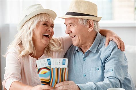 여행사에 앉아 있는 모자를 쓴 선배 부부는 여권과 티켓을 들고 서로를 쾌활하게 바라보고 있습니다 고객에 대한 스톡 사진 및 기타 이미지 Istock