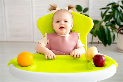 아이는 부엌에서 높은 의자 이유식 개념에서 빨간 사과 또는 과일을 먹고 어린 아기 소녀는 과일 퓌레를 스스로 먹습니다 6 11 개월에 대한 스톡 사진 및 기타 이미지