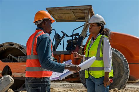 안전 장비를 착용한 토목 기사와 건축가가 건설 현장을 검사합니다 옥외 구조 건축 현장을 검사하고 작업하는 엔지니어 엔지니어링 및