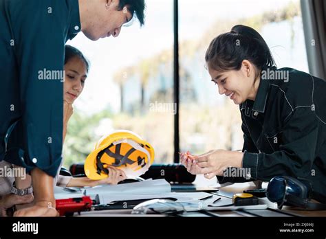 Group Of Engineers Collaborating On A Project In A Modern Office Environment With Safety Gear