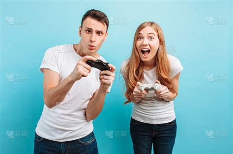 一对兴奋的年轻夫妇一男一女手里拿着操纵杆在蓝色背景下玩电子游戏