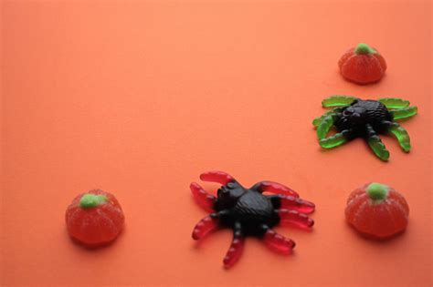 밝은 주황색 배경에 녹색과 빨간색 다리와 호박거대한 검은 거미의 형태로 달콤한 젤리 사탕 공간을 복사합니다 달콤한 헬로웬 트릭 또는 치료 개념 0명에 대한 스톡 사진 및