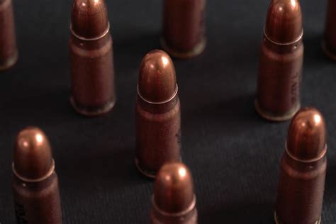 Premium Photo Bronze Pistol Bullets Arranged Next To Each Other On Black Board Closeup Detail