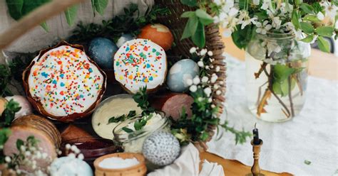 전통적인 부활절 바구니 부활절 현대 계란 부활절 빵 햄 사탕무 버터 녹색 회양목 가지와 촛불이 있는 나무 테이블에 꽃으로 장식된 소박한 바구니에 담긴 소시지 사진