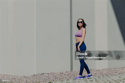 스포츠 복에서 활동적인 적합 여성의 수평 샷은 자신있게 거리로 보인다 그늘을 착용 좋은 야외 운동 후 휴식 그녀의 건강과 그림의 관심 사람 건강한 라이프 스타일 가냘픈에