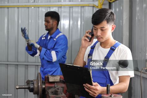 금속 선반 기계를 사용하는 다민족 기술자 정비사는 차고에서 스마트 휴대폰과 클립 보드로 자동차 디스크 브레이크 연마를 작동합니다 유지 보수 자동차 및 검사 차량 부품 개념
