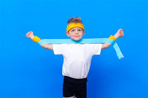 파란색 스튜디오 배경 위에 고무 피트니스 밴드와 스포티 한 작은 소년 체육관 운동 어린이 스포츠맨 활동 스포츠 건강 및 에너지 성공 건강한 생활방식에 대한 스톡 사진 및