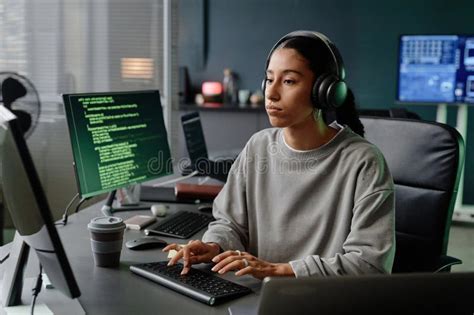 Middle Eastern Female Developer Coding On Computer Wearing Headphones In Office Stock Image