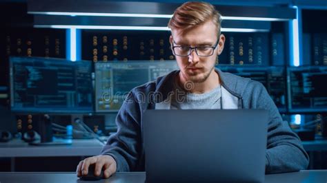 Portrait Of Software Developer Hacker Wearing Glasses Sitting At His Desk And Working On