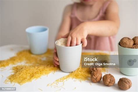 아기 소녀 테이블에서 곡물 견과류 파스타 및 쌀을 가지고 노는 유아 감각 조기 발달 아기 어린이를위한 교육 아이 유용한 게임 미세 운동 기술 개념 복사 공간 몬테소리 교육에