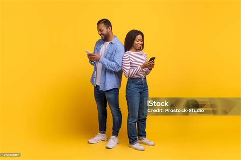 노란색 배경에 스마트폰을 사용하며 등을 맞대고 서 있는 두 사람 컷아웃에 대한 스톡 사진 및 기타 이미지 컷아웃 남자 서 있기 Istock