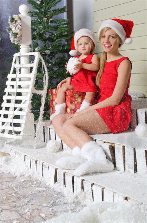 Het Mamma En De Dochter In Kerstman` S Kostuums Zitten Onder Sneeuw