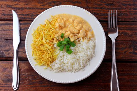 치킨 스트로가노프는 소박한 나무 테이블에 토마토 추출물 쌀 감자 칩을 곁들인 사워 크림으로 구성된 러시아 요리에서 유래한 요리입니다 맨 위 보기 소고기 스트로가노프에 대한