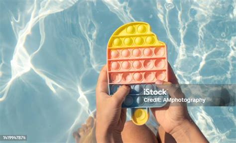 파란 수영장 물에 대하여 그것을 팝으로 노는 소녀아이 아이스크림 모양을 들고 팝 그것 실리콘 장난감 손가락으로 누르는 감각 지각에 대한 스톡 사진 및 기타 이미지 Istock