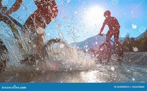 Silhouette Friends Spraying Water At Camera While Riding Bicycles In