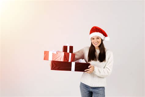 빨간 산타 모자와 흰색 스웨터를 입고 흰색 배경과 함께 크리스마스 선물 상자를 들고 흥분 아름다운 젊은 여자 25 29세에 대한 스톡 사진 및 기타 이미지 Istock