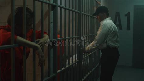 Shocked Female Prisoner Holds Metal Bars Stands In Prison Cell In