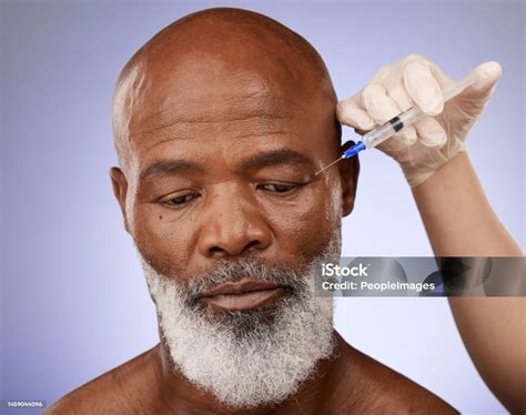 손 얼굴 보톡스는 보라색 배경에 스튜디오에서 주사기 주사를 받는 고위 흑인 남성입니다 성형 수술 노화 방지 및 성형 수술을위한 살롱에서 성숙한 남성과의 치료 남자에 대한