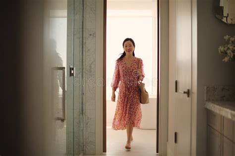 Woman In Floral Dress Enters A Bright Bathroom With A Relaxed And