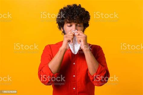 오렌지색 벽 배경 위에 고립되어 서 있고 손수건이나 조직에 재채기를하고 독감 알레르기로 아픈 느낌을주는 아픈 인도 남자 코 풀기에 대한 스톡 사진 및 기타 이미지 Istock