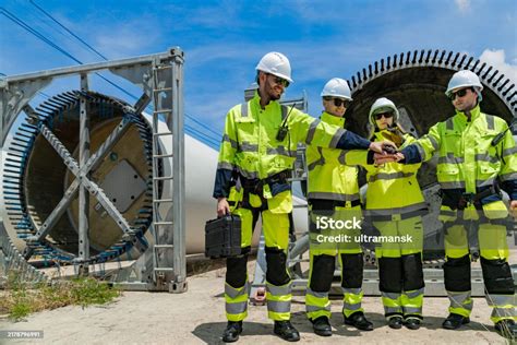 안전 장비를 착용한 엔지니어가 건설 현장에서 풍력 터빈 블레이드 부분을 검사하고 있습니다 그들은 금속 프레임워크를 정밀하게