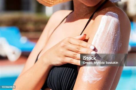 화창한 여름 날에 수영장 옆에서 무두질 한 어깨에 손으로 선 크림을 바르는 예쁜 여성 휴가 개념의 자외선 차단 요소 수영장 스포츠 경기장에 대한 스톡 사진 및 기타 이미지