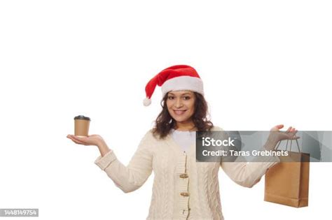 산타 모자를 쓰고 카메라에 미소를 짓고 테이크아웃 뜨거운 커피나 차와 종이 봉지의 일회용 컵을 들고 있는 예쁜 여자 개념에 대한 스톡 사진 및 기타 이미지 Istock