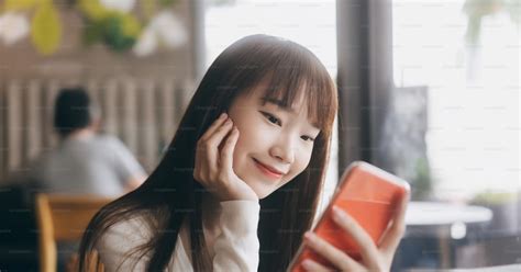 대학생들은 낮 시간 개념에 따라 생활 방식을 교육하고 공부합니다 젊은 성인 아시아 여학생이 실내 카페에서 온라인 신청을 위해 휴대폰을 사용하고 있다 사진