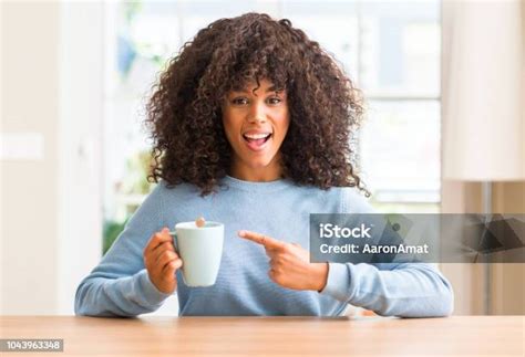 손과 손가락으로 가리키는 매우 행복 가정에서 커피 한 잔을 들고 아프리카계 미국인 여자 가리키기에 대한 스톡 사진 및 기타 이미지 가리키기 감정 곱슬 머리 Istock