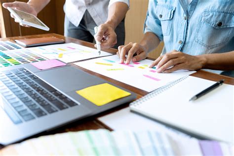 새로운 제품을 설계하는 사무실에서 일하는 젊은 디자이너의 그룹 새로운 스마트 폰 디자인 개념에 대한 색상 차트 및 컴퓨터 노트북을 사용 광고에 대한 스톡 사진 및 기타