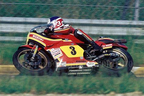A Man Riding On The Back Of A Red Motorcycle Down A Race Track In Front