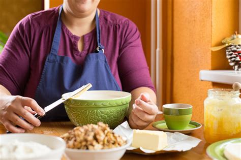 나무 식탁 그녀의 손에 칼을 들고와 그릇의 가장자리에 버터 한 조각을 닦아에 초점 뒤에 앉아 젊은 여자의 사진을 닫습니다 가정 생활에 대한 스톡 사진 및 기타 이미지