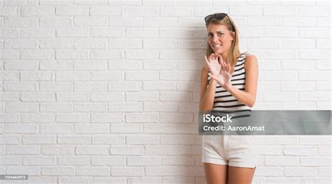 흰색 벽돌 벽을 통해 젊은 아름 다운 금발의 여 자가 혐오 식 불쾌 하 고 두려워 하기 때문에 역 겨 운 얼굴을 하 고 혐오 반응 손으로 발생합니다 성가신 개념입니다 감정에