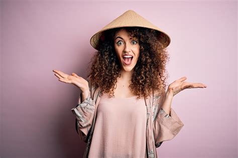 곱슬 머리와 피어싱 전통적인 아시아 원추형 모자를 입고 젊은 아름다운 여자는 미친 축하와 팔을 들고 흥분 비명을 지르는 눈을