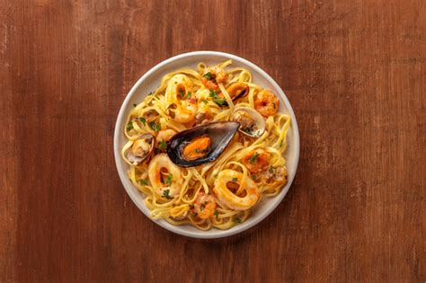 해물 파스타 홍합 새우 조개와 오징어 반지가 있는 Tagliolini 접시는 어두운 소박한 나무 배경의 상단에서 텍스트를 위한