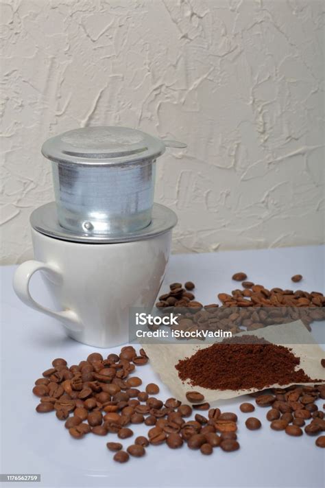 베트남 커피 메이커와 커피 한 잔 커피 알갱이와 약간의 분쇄 커피가 테이블 표면에 흩어져 있습니다 세계 커피의 날 0명에 대한