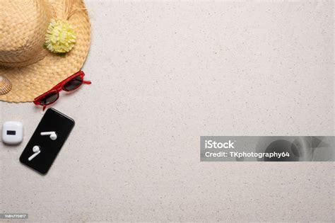 여름 해변 휴가 컨셉으로 자유로운 텍스트 공간을 즐길 수 있다 평면도 여성용 빨대 선글라스 모자 고운 모래 배경에 무선 이어폰이 있는 스마트폰이 있는 평면 레이아웃 관광에