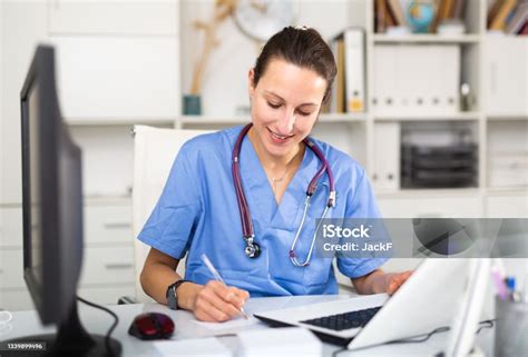 젊은 여성 의사는 주민의 사무실에서 컴퓨터에 앉아있는 동안 중요한 메모를합니다 25 29세에 대한 스톡 사진 및 기타 이미지 25 29세 30 34세 가구 Istock