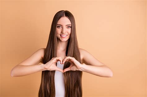 귀여운 달콤한 귀여운 아가씨 의 초상화 확인 심장 원하는 날짜 쇼 사랑 남자 친구가 절차 부드러운 실크 헤어 스타일 옷을 입고 흰색 상단 단일 옷 고립 된 베이지 색 배경