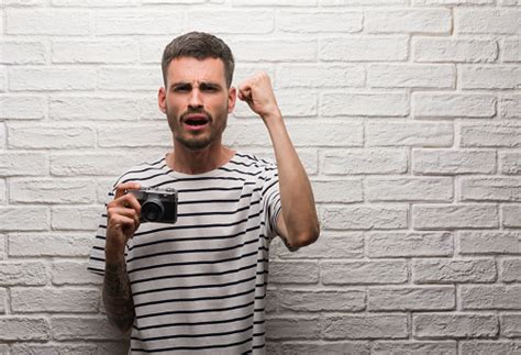 흰색 벽돌에 빈티지 카메라 서 개최 하는 젊은 남자 화가 좌절 분노 미친 제기 손으로 소리와 분노 개념 소리 벽 감정에 대한