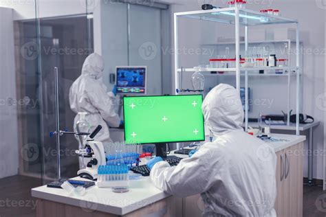 Scientist Conducting Experiment Using Computer With Green Screen Sitting His Workpalce In Lab