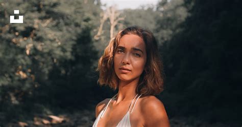 흰색 스파게티 스트랩 탑과 파란색 데님 반바지를 입은 여자가 낮에 갈색 모래 위에 서 있다 사진 Unsplash의 무료 여자 이미지