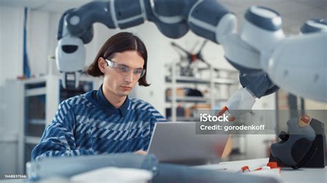 노트북에 로봇 팔을 프로그래밍하는 남성 개발자 로봇 공학 엔지니어는 3d Cad 소프트웨어를 사용하여 설계를 작성합니다 획기적인 프로젝트 및 컴퓨터 과학 고등 교육 개념