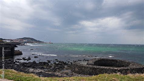 흐린 하늘 속 햇빛이 내리치는 바닷가 풍경 스톡 사진 Adobe Stock