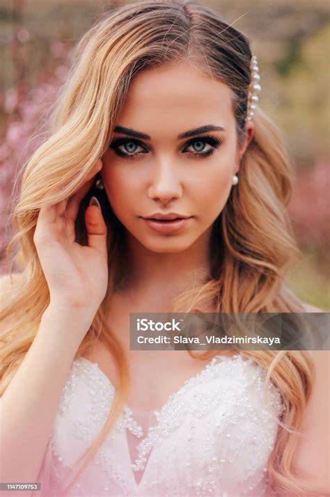 정원에서 꽃 복숭아 나무 중 포즈 우아한 웨딩 드레스에 금발 머리를 가진 아름 다운 여자 개인 장식품에 대한 스톡 사진 및 기타 이미지 개인 장식품 관능 귀걸이