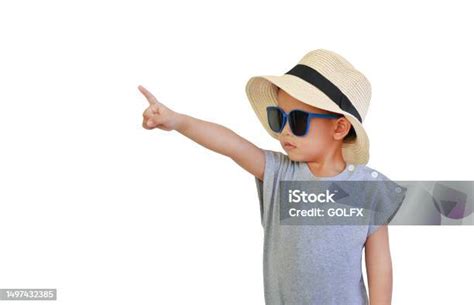 어린 아시아 소년은 하얀 배경에 고립되어 있는 옆과 위를 가리키고 있다 여름 드레스를 입고 선글라스를 쓴 모자를 쓴 아이 휴일과 여름 패션 컨셉 2 3 살에 대한 스톡 사진